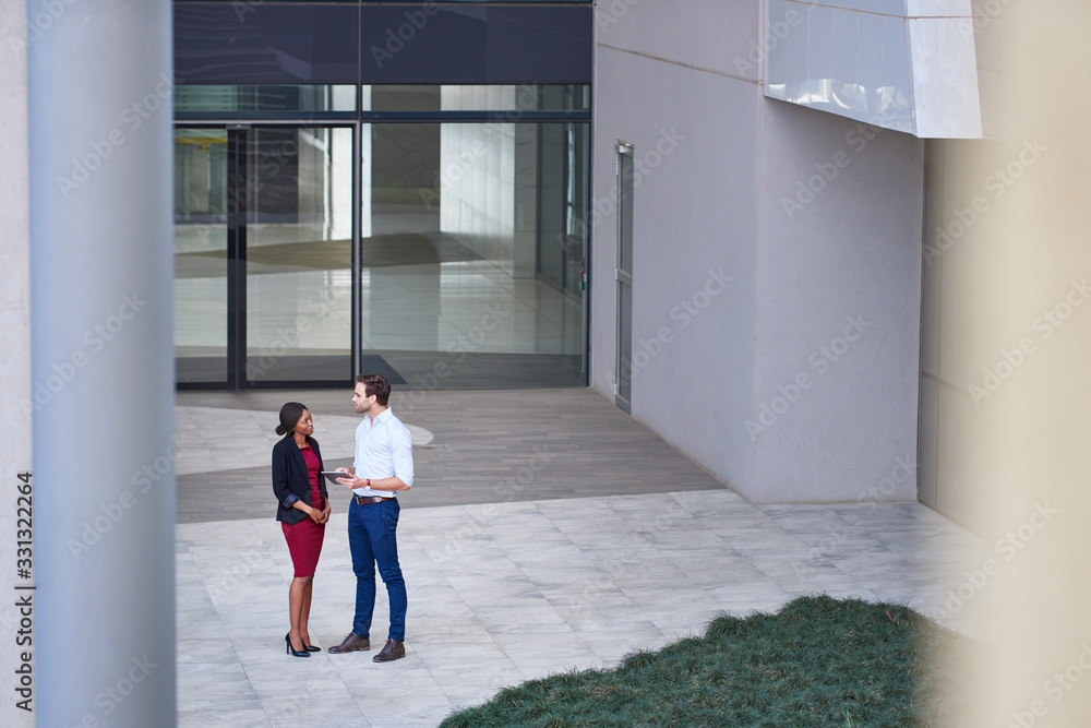 Diverse young businesspeople talking outside of an office building ...