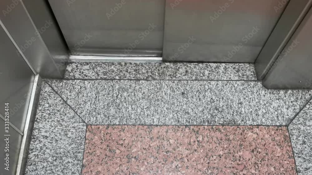 POV. Granite flooring. The steel elevator door is opened. Feet in brown ...