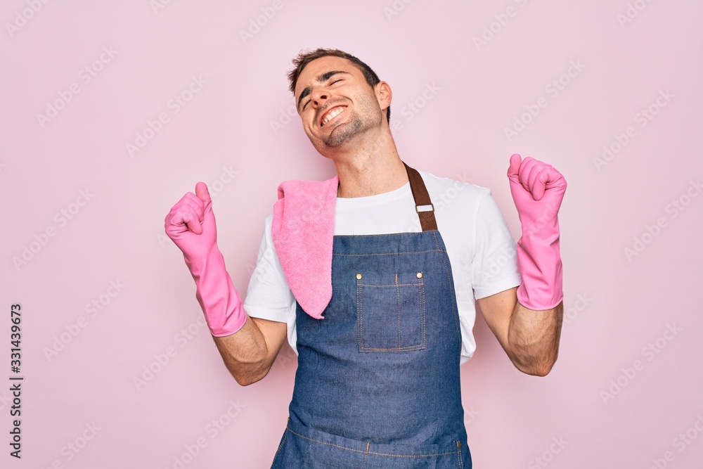 Young cleaner man with blue eyes cleaning wearing apron and gloves over ...