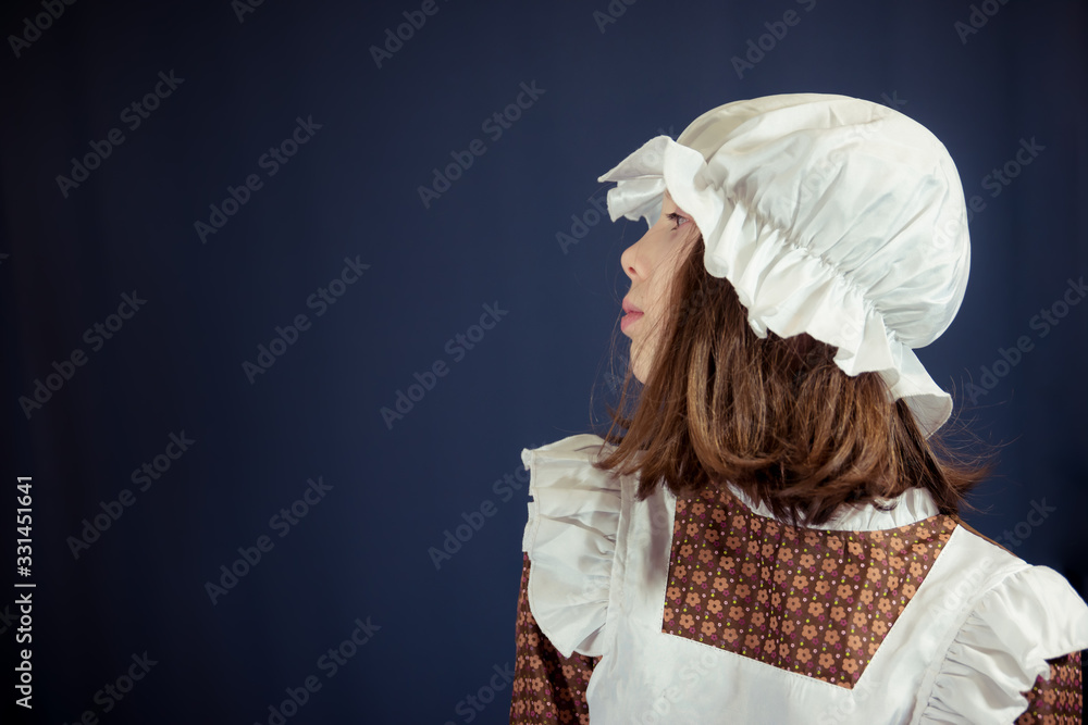 Girl in Victorian maid costume with mob cap - looking towards white ...