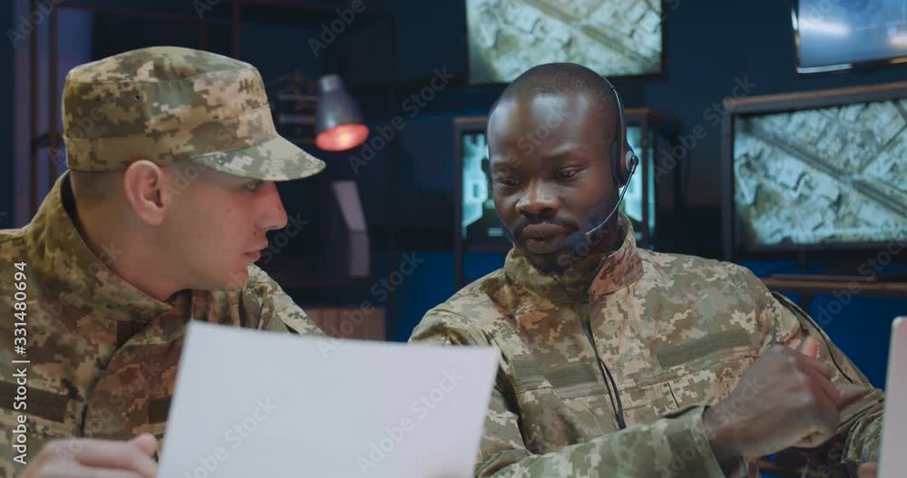 Multiethnic male co-workers sitting in control room and studying ...