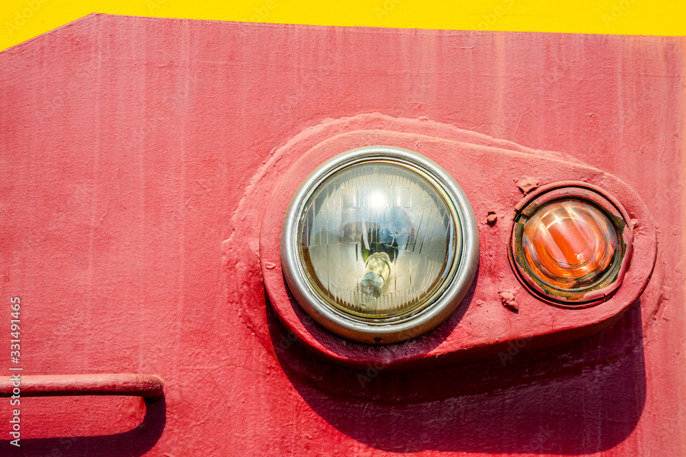 Electric headlight and a red metal body of a vintage diesel engine ...