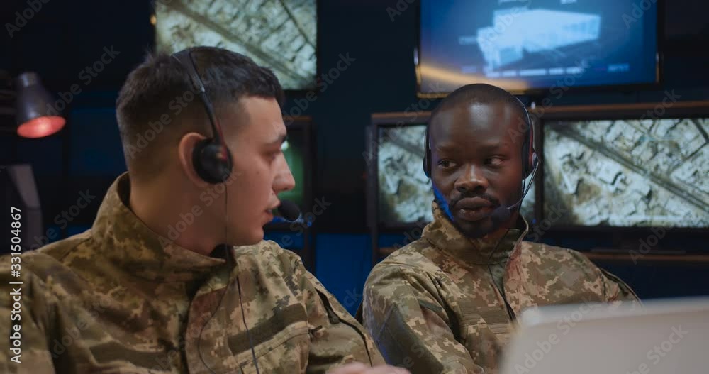 Multiethnic male military dispatchers colleagues in headsets sitting in ...