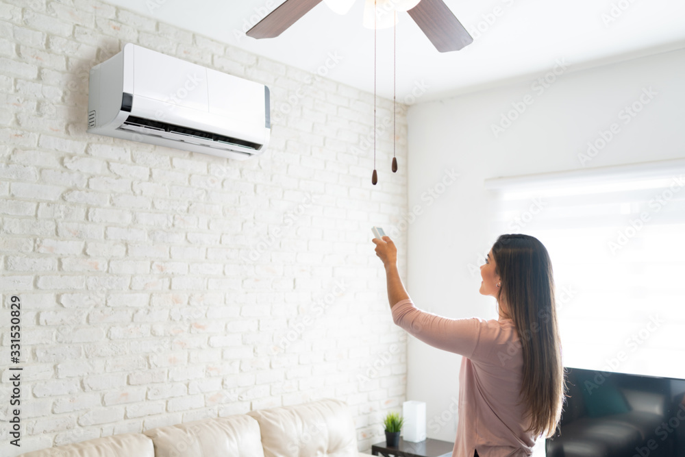 Woman Adjusting Temperature Of Air Conditioner With Remote Stock Photo ...