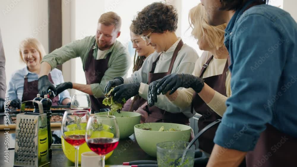 Diverse group of cooking class students in aprons and gloves are making ...