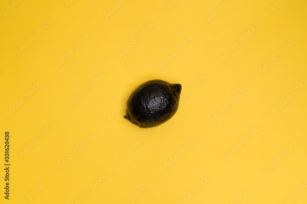 Black lemon on the yellow background. Minimal style. Top view. The ...