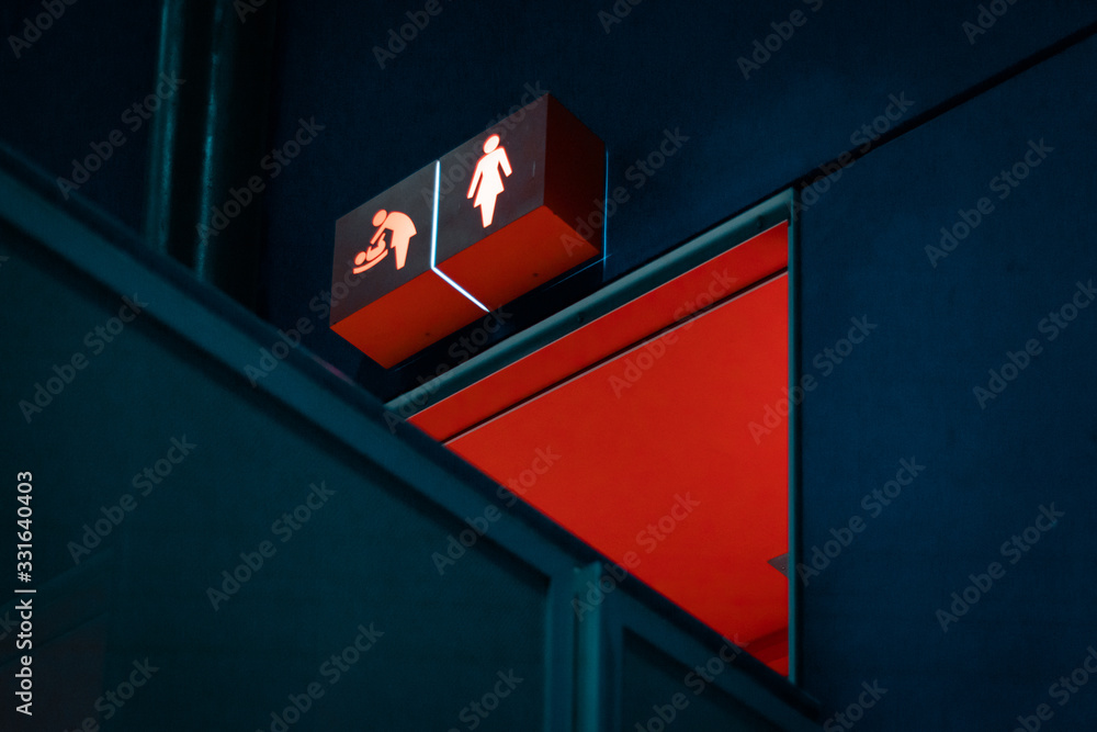 Red emergency toilet sign on the wall. Blue modern architecture, public ...