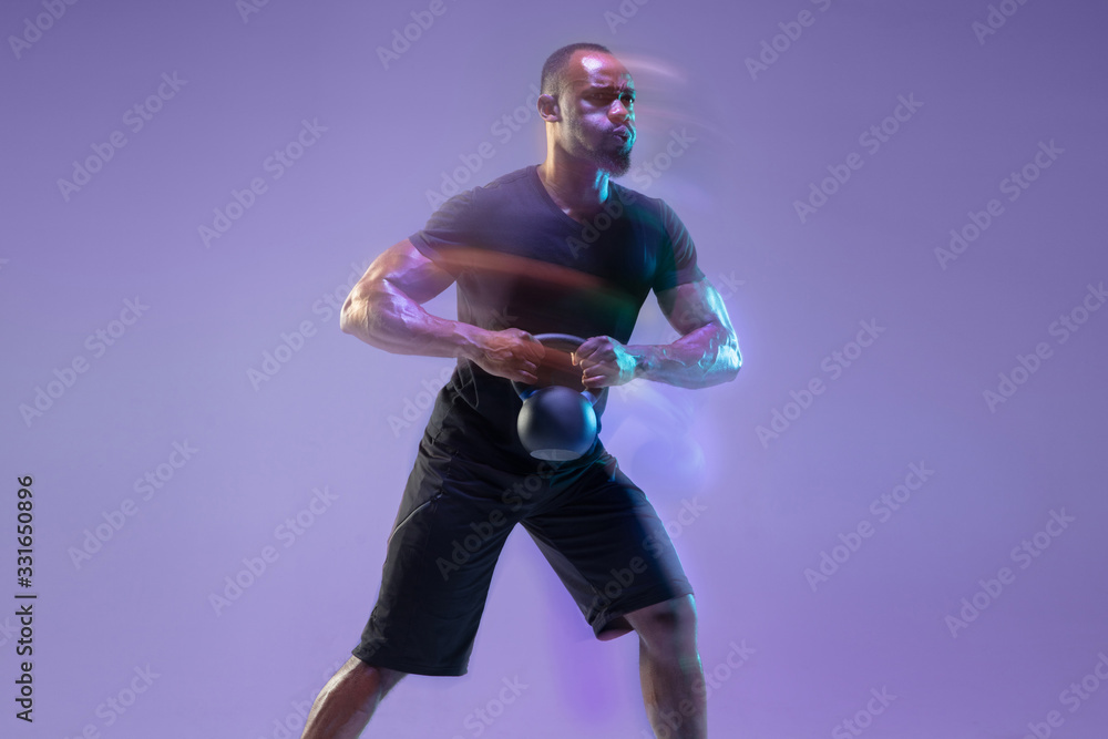 Emotional. Young african-american bodybuilder training over purple ...