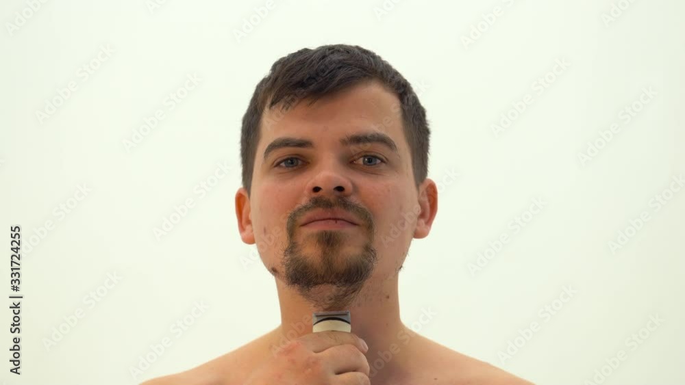 Vidéo Stock A young man shaves off his beard with an electric razor ... Vidéo Stock A young man shaves off his beard with an electric razor ...