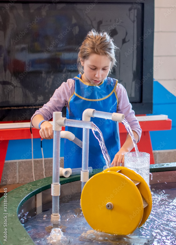 Young girl learns how water flows as she plays on a water table Stock ...