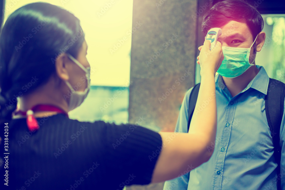 Staff check fever by digital thermometer visitor at Information counter ...