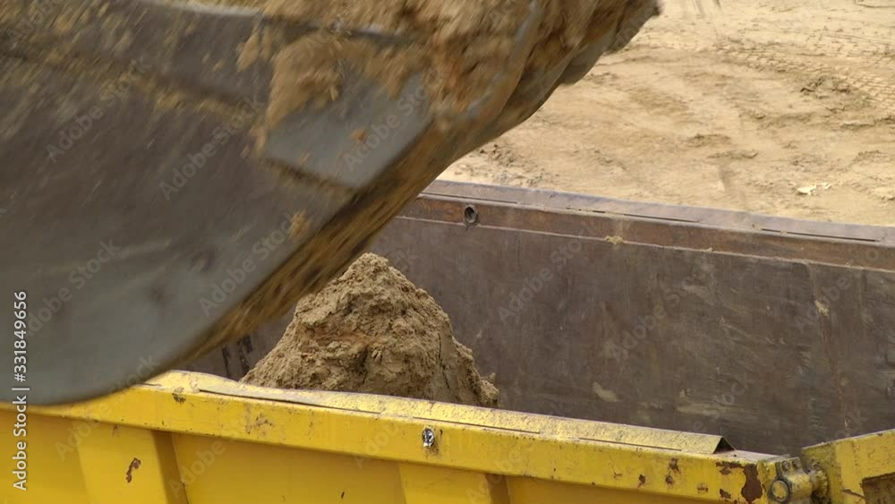 Bulldozer excavator loading ground to tipper truck on the street ...
