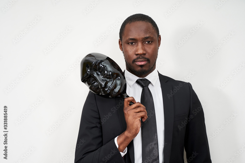 African young man wearing black suit taking off plastic mask revealing ...