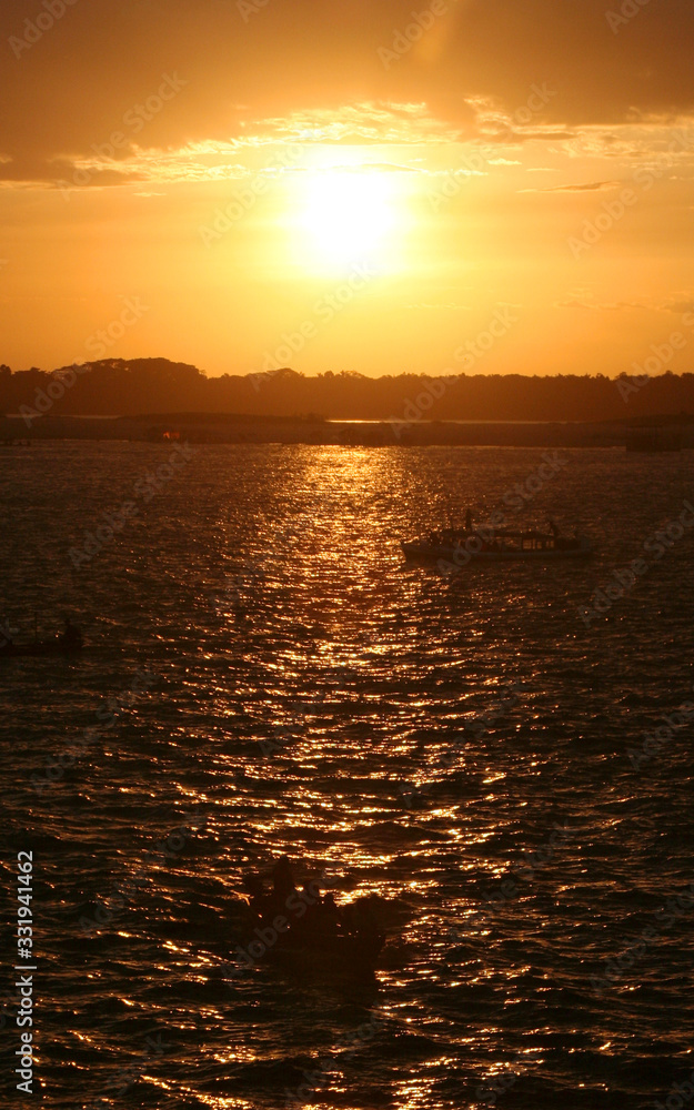 Silhueta de barcos atravessando rio com ondas em contraluz durante o ...