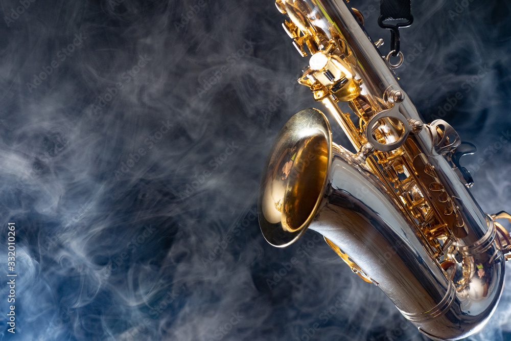 Poster Golden shiny alto saxophone on black background with smoke ...