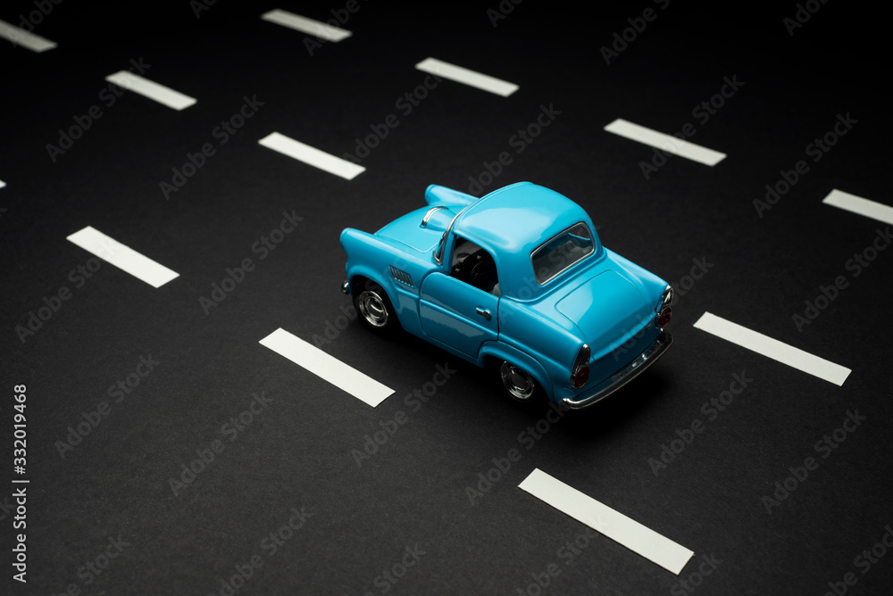 Top and rear view of a blue colored fifties toy model car on an asphalt ...