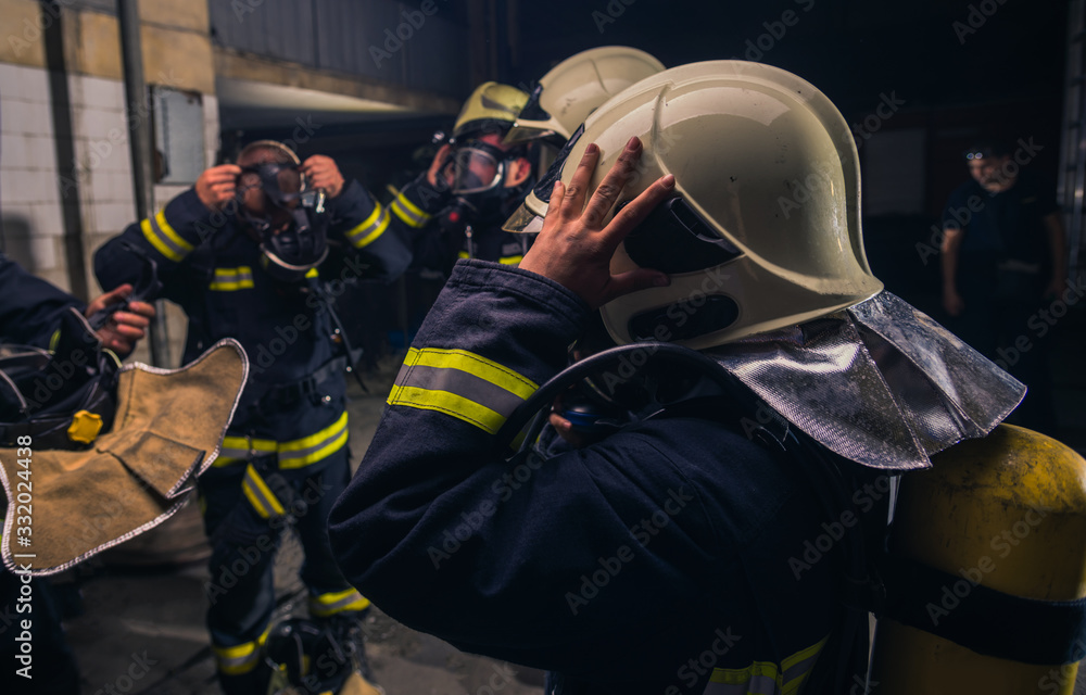 Group of firefighters standing inside the fire brigade wearing helmet ...