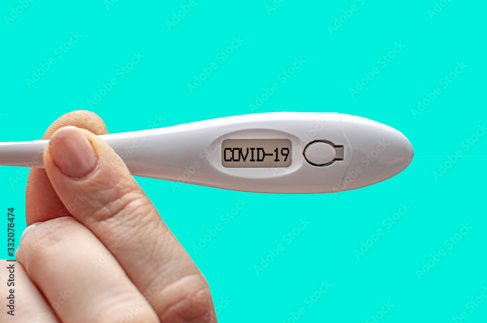 A thermometer in female hands shows the word COVID-19. Temperature ...
