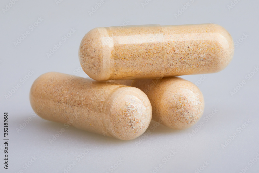 Transparent gelatin capsules with organic powder on white background ...