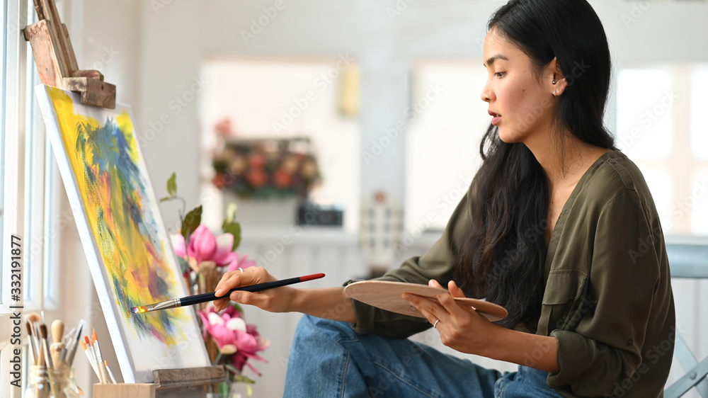 Young beautiful artist girl concentrated on painting while sitting in ...
