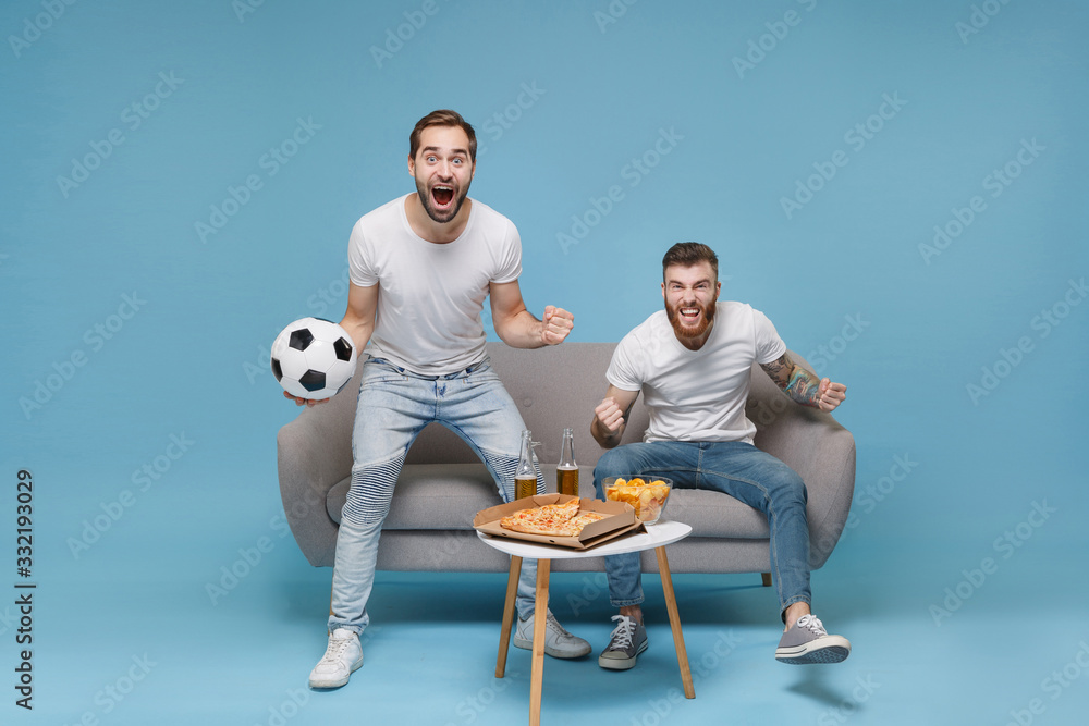 Excited young men guys friends in white t-shirt sit on couch isolated ...