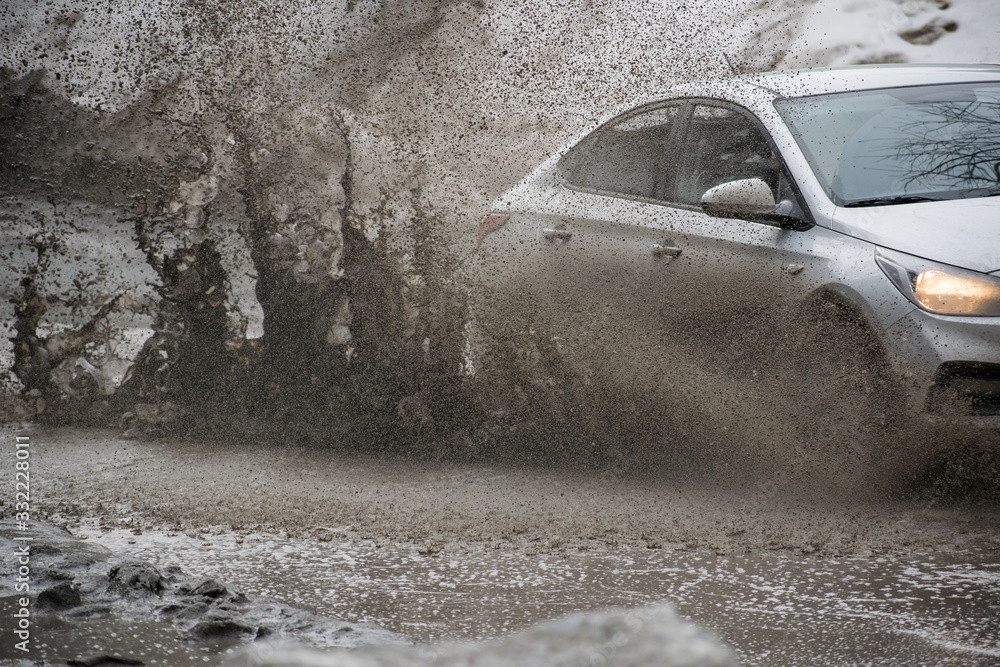 Car motion through big puddle of water splashes from the wheels on the ...