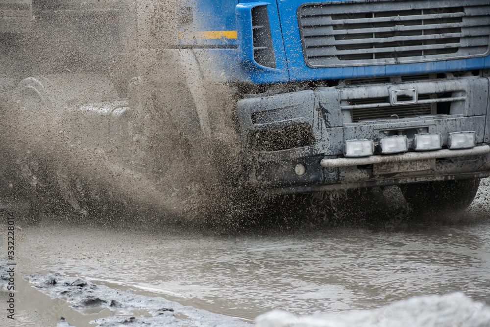Car motion through big puddle of water splashes from the wheels on the ...