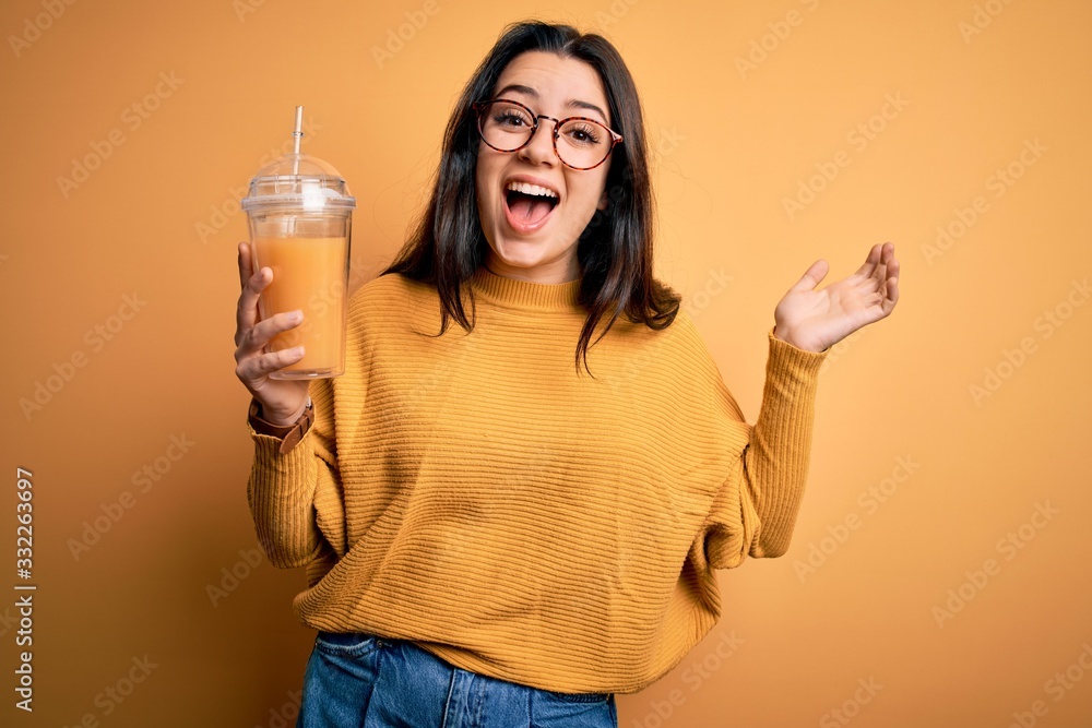 Young brunette woman drinking fresh orange juice from take away bottle ...