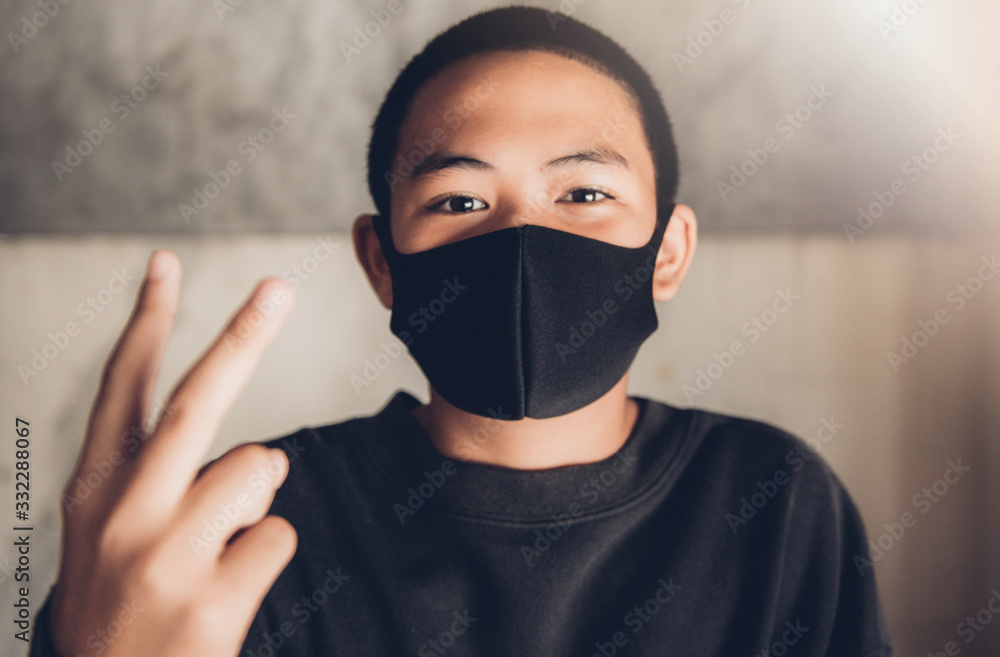 The boy, wearing a black mask, covered his nose and mouth on his face ...