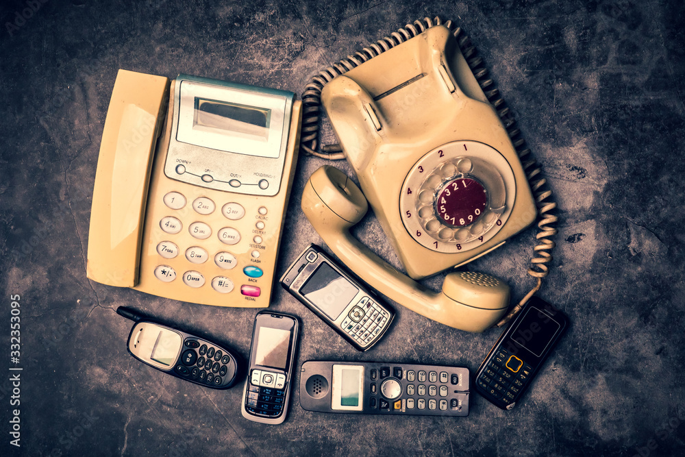 An old telephone with rotary dial, landline and obsoleted cellphone on ...