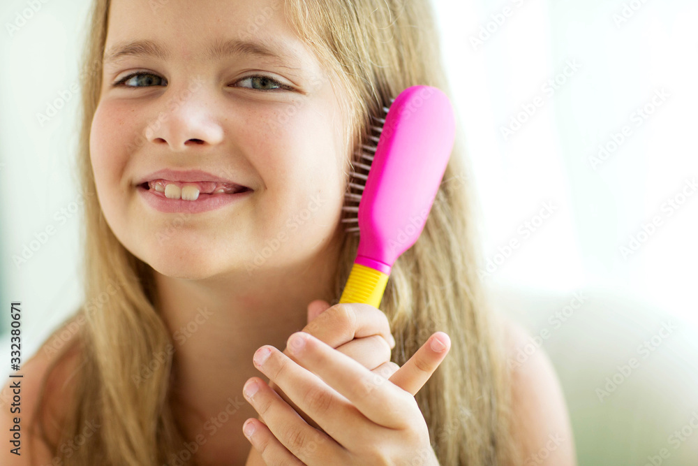 Child with a comb. Little girl combing her hair with a tinted comb ...