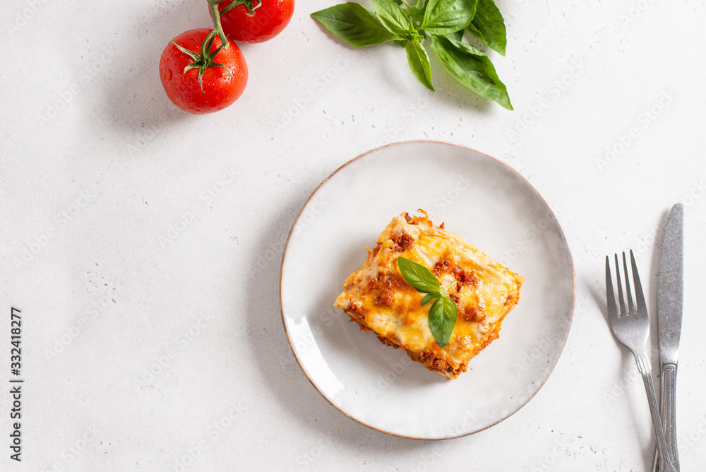 Piece of tasty hot lasagna served with a basil leaf on a gray plate ...