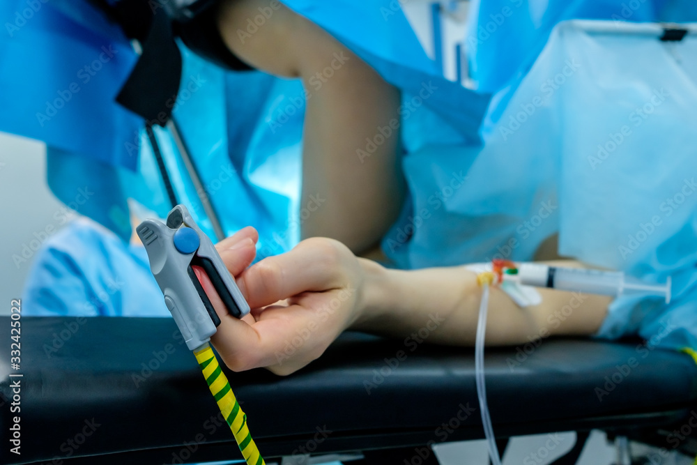 Hand of the patient lying on the operating table. On the finger is a ...