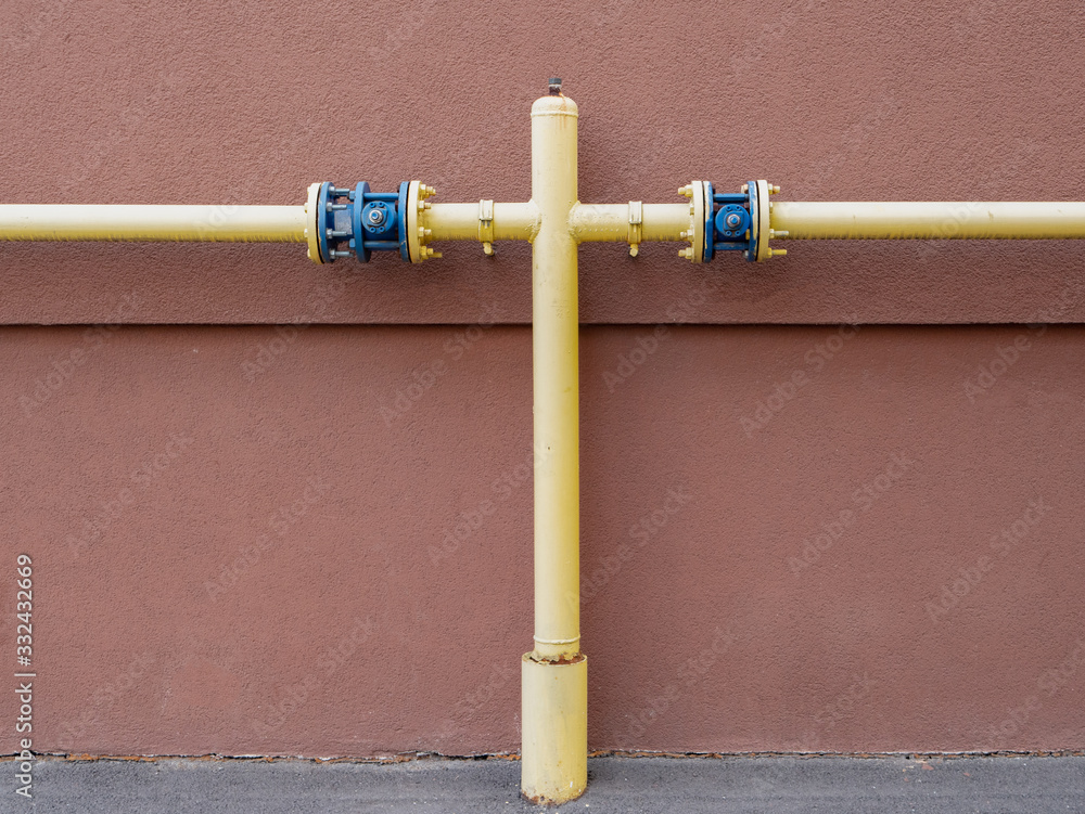 yellow water gas utility pipe branching with painted concrete wall on ...