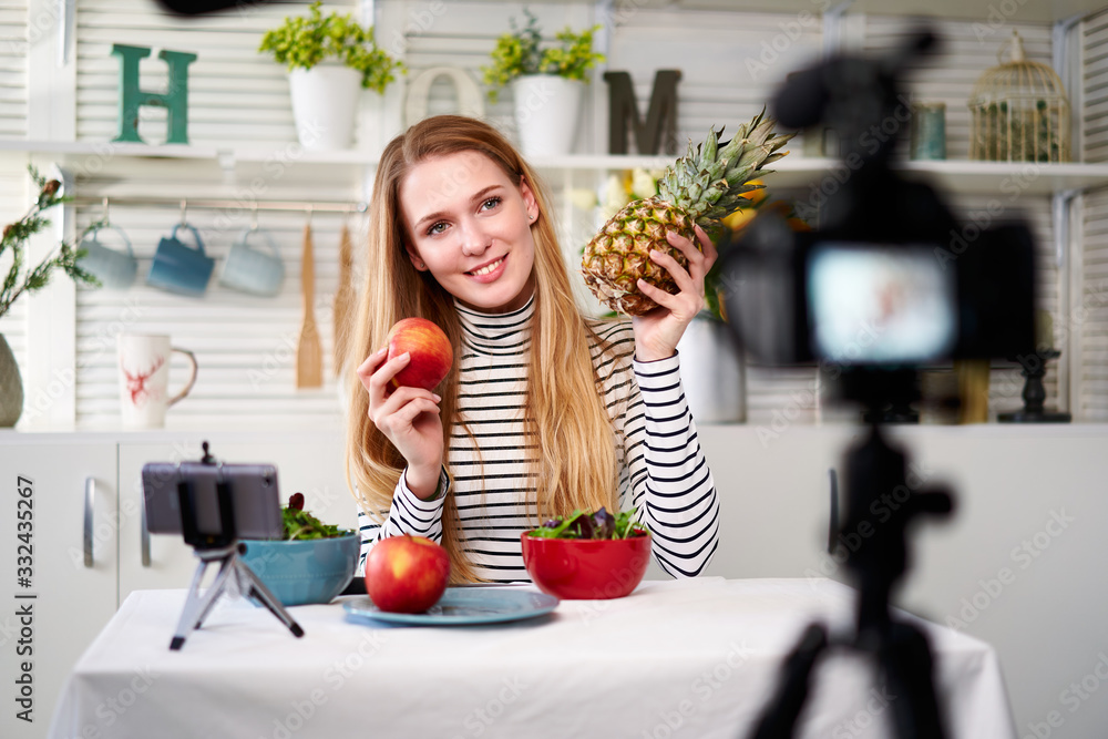 Food blogger cooking fresh vegan salad of fruits in kitchen studio ...