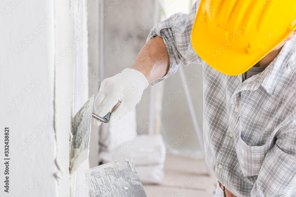 Builder using a trowel to add plaster to a wall Stock Photo | Adobe Stock