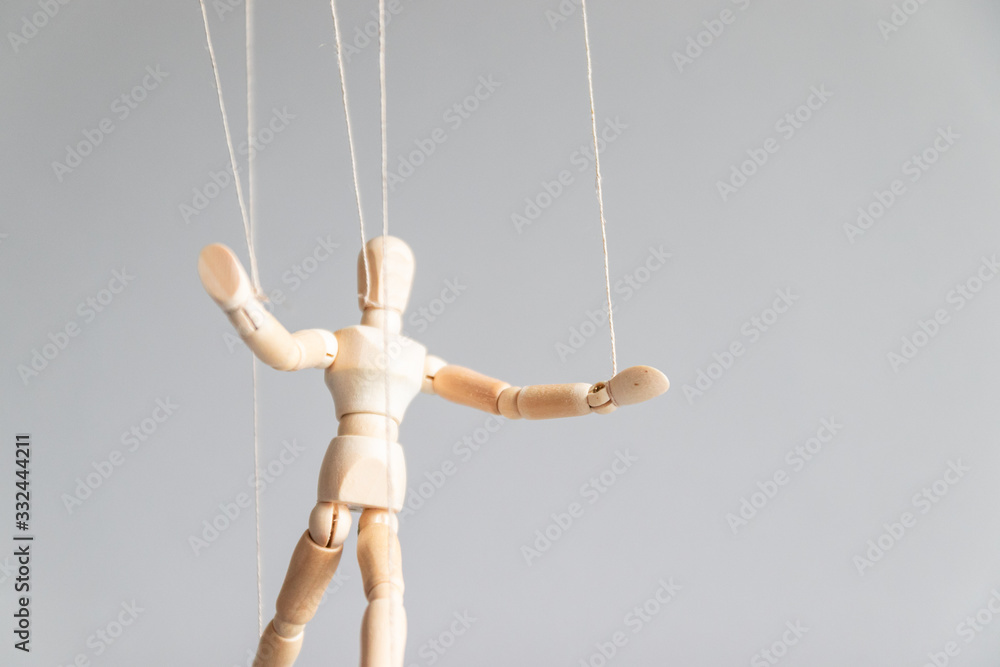 Human control concept. Wooden puppet doll on the clothesline on a gray ...