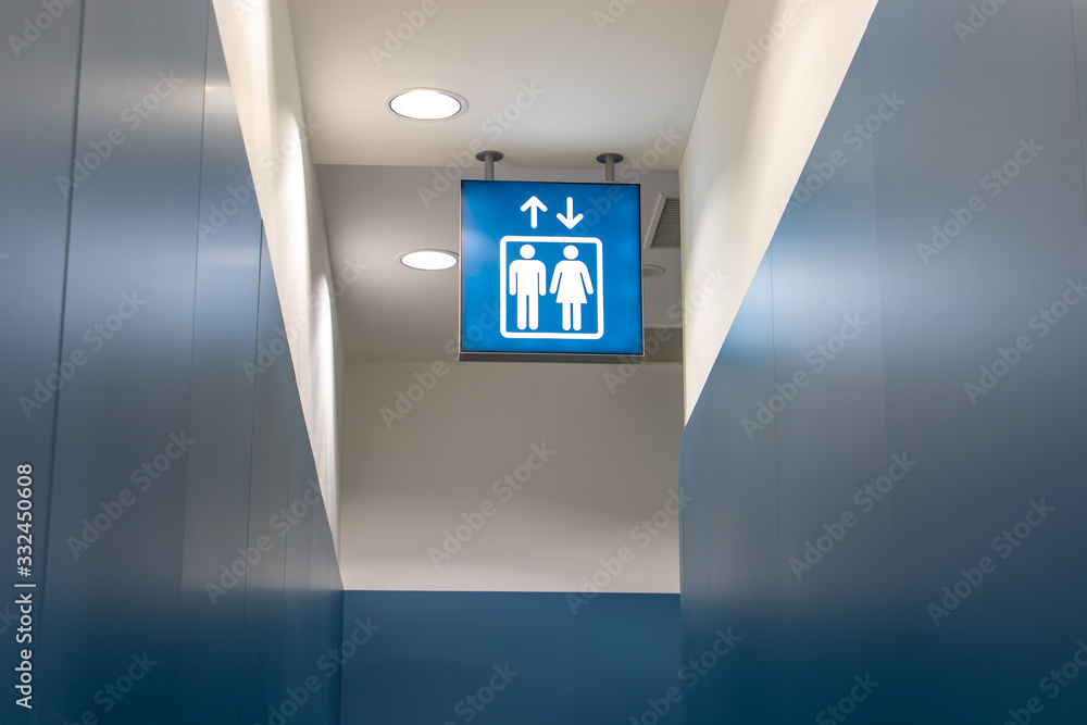 An illuminated sign with the icon of a lift hang on ceiling of the blue ...