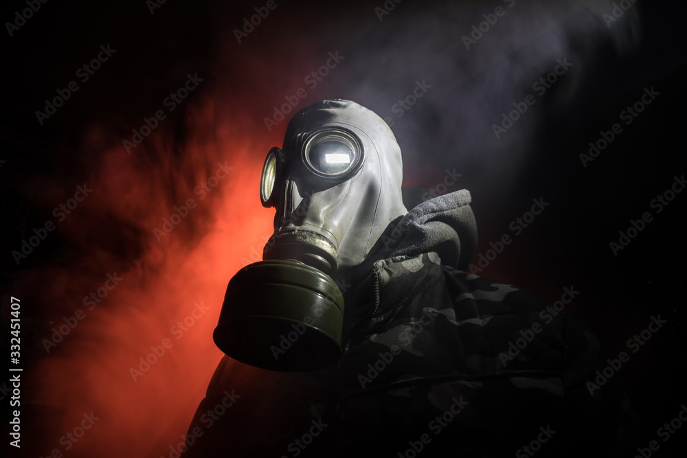 Gas mask with clouds of smoke on a dark background. Sign of radioactive ...