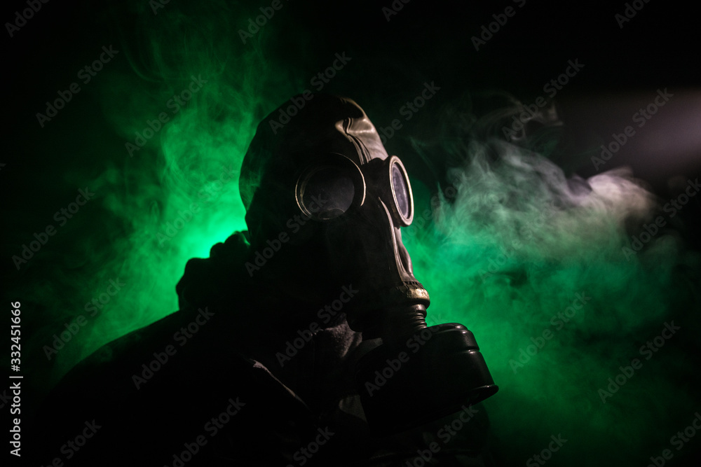 Gas mask with clouds of smoke on a dark background. Sign of radioactive ...