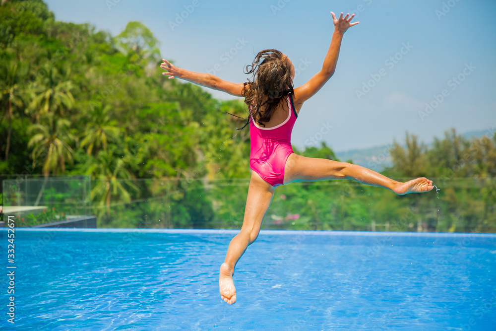 Excited funny little girl jumping to the swimming pool. Happy summer ...