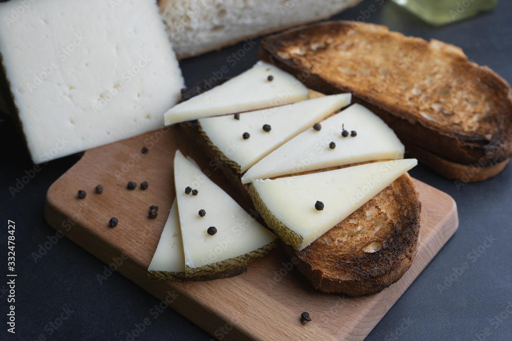 Queso manchego sobre una rebanada de pan tostado con algunos granos de ...