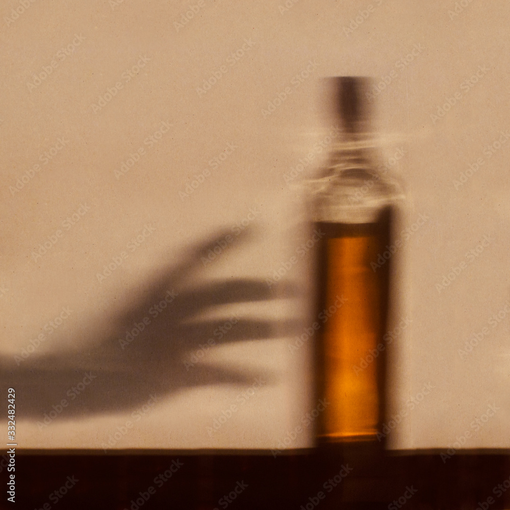 Alcohol addiction concept - shadow of hand reaching for bottle of ...