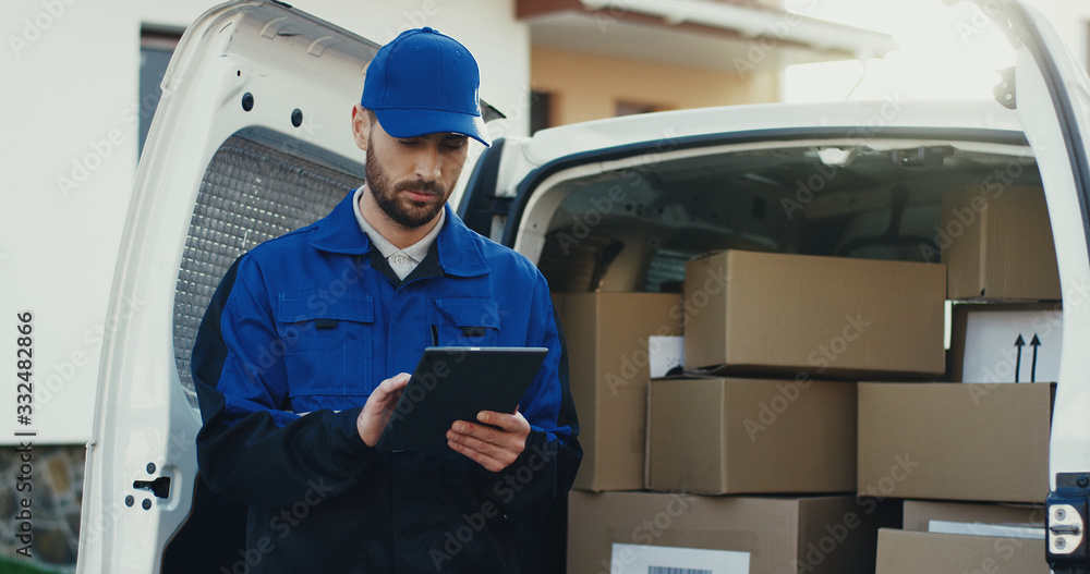 Caucasian good looking mailman in blue costume and cap checking the ...