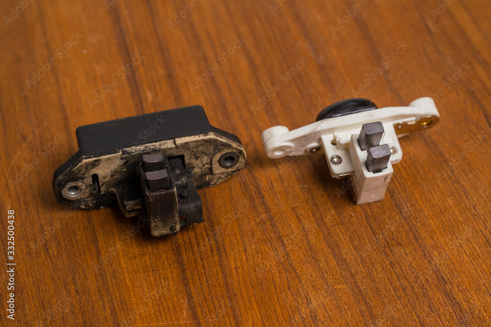 Comparison of old and new alternator brushes and regulator on a wooden ...