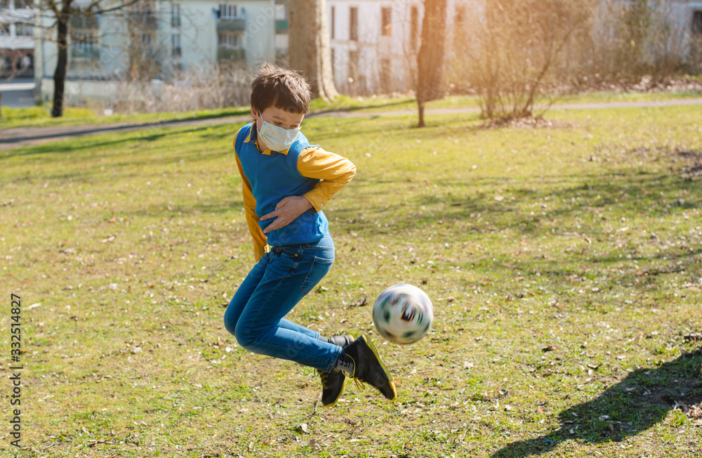 Boy playing football in the park despite the Covid-19 crisis Stock Photo | Adobe Stock