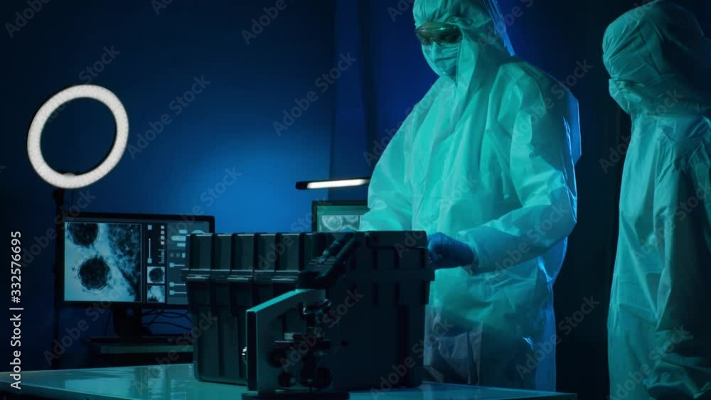 Scientists in protection suits and masks working in research lab using ...