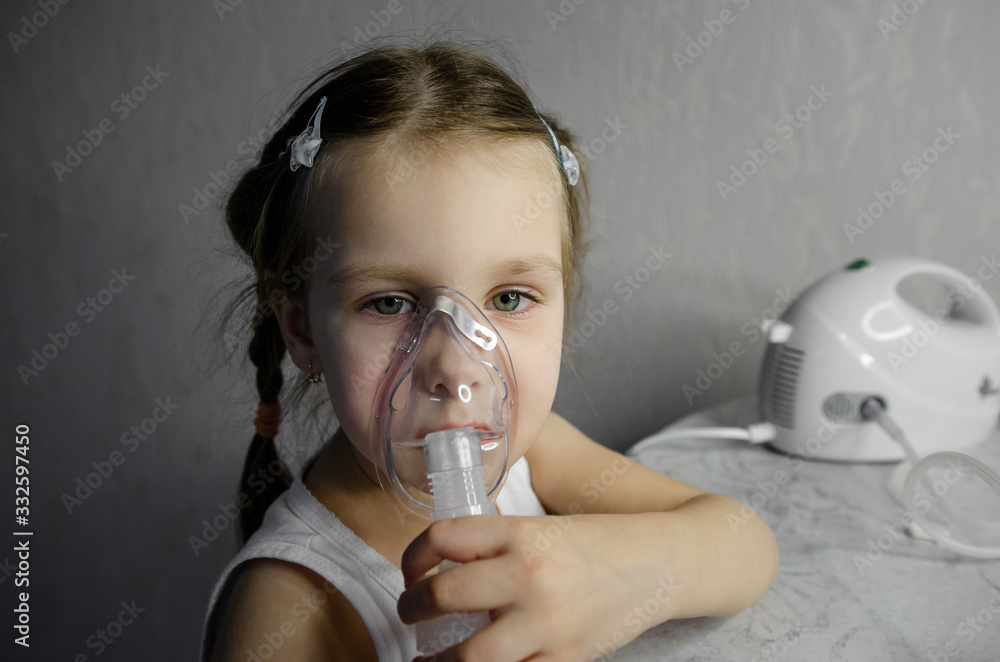 A child sits with an inhaler at home. Coronovirus treatment concept ...
