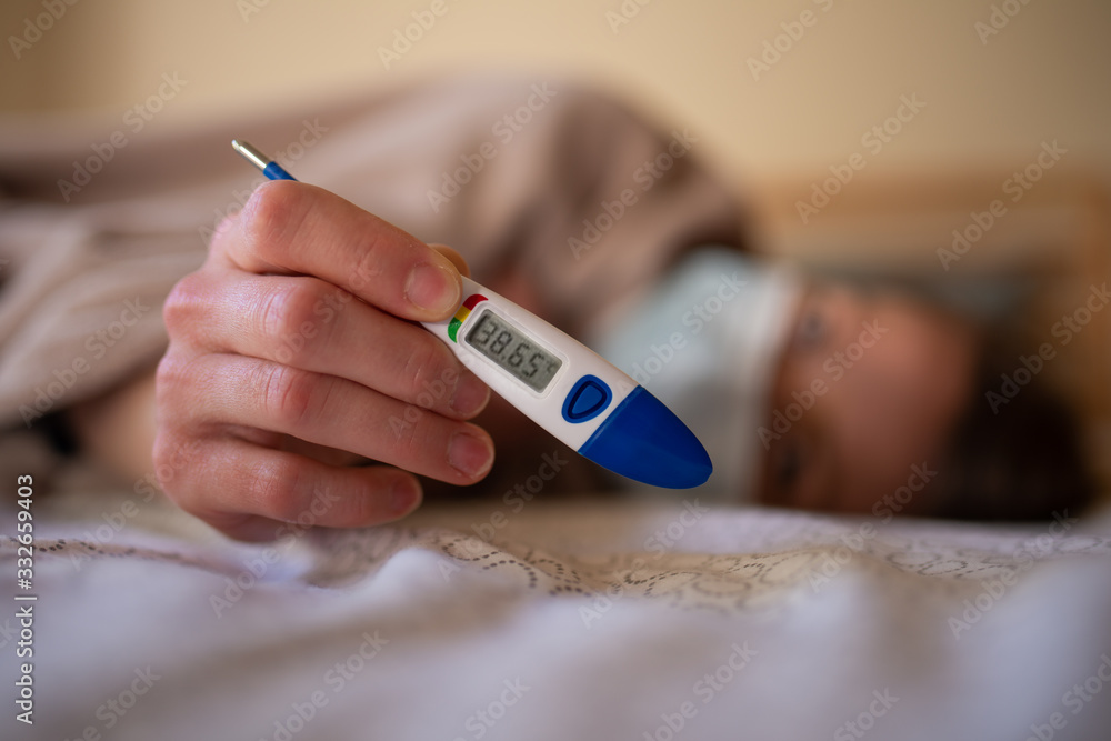 The girl measures the temperature at home, fever is a sign of ...