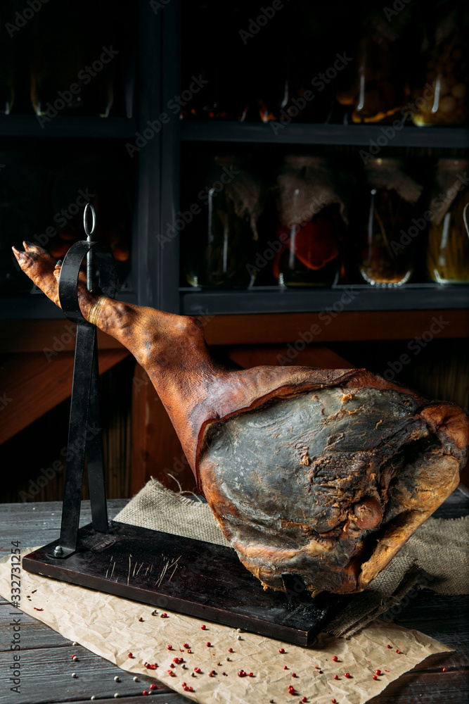 Spanish delicatess smoked pork leg for slicing on a holder, on rustic ...